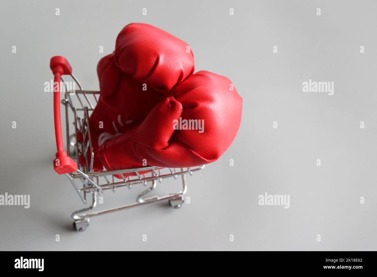 Boxing gloves inside shopping trolley with copy space. Fight inflation ...