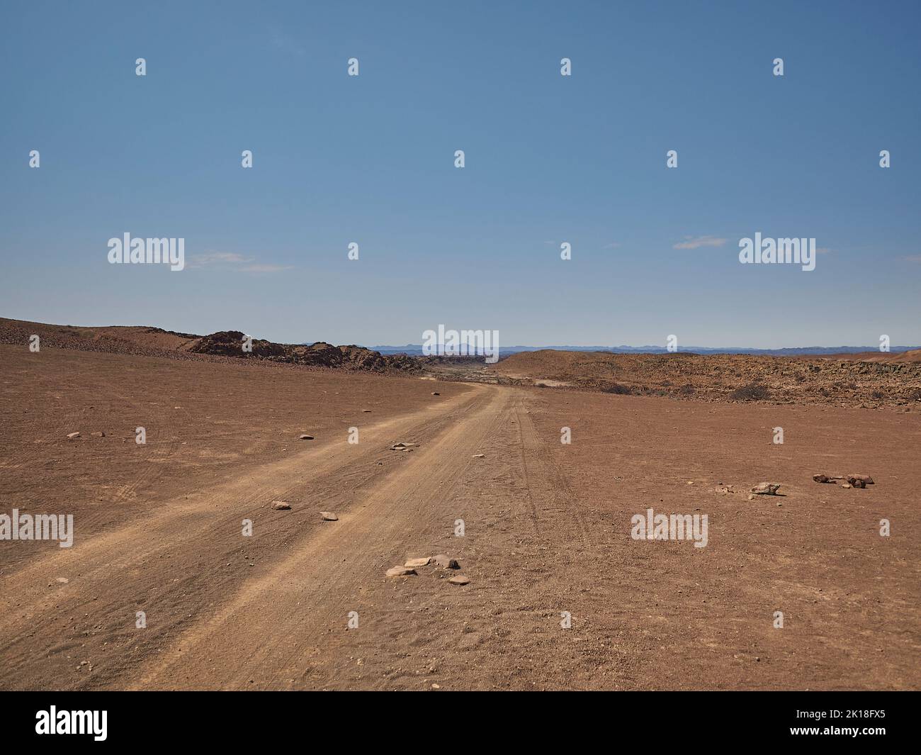Gravel road through the arid region of the Damarland Namibia leading to the horizon into nowhere ...