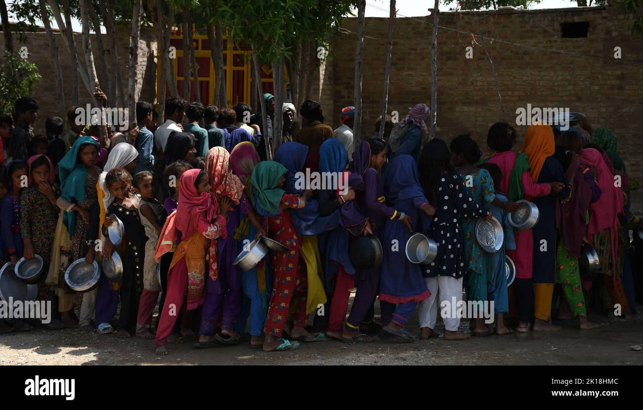 People affected by floods receive water in flooded areas in Sehwan ...