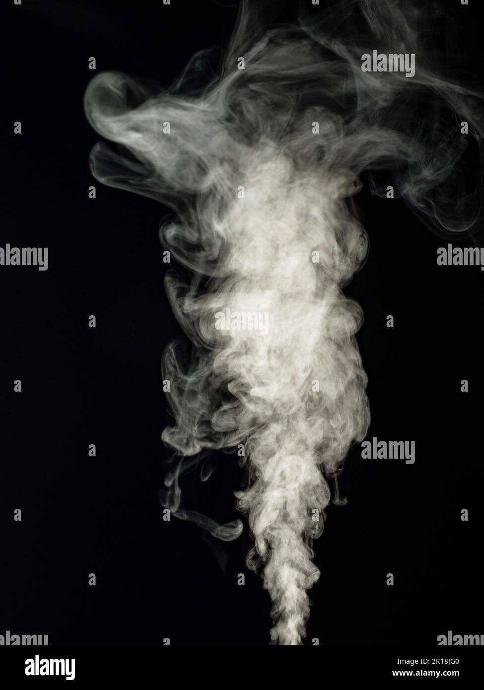 Fluffy white smoke on a black background, swirls and rises upwards as ...