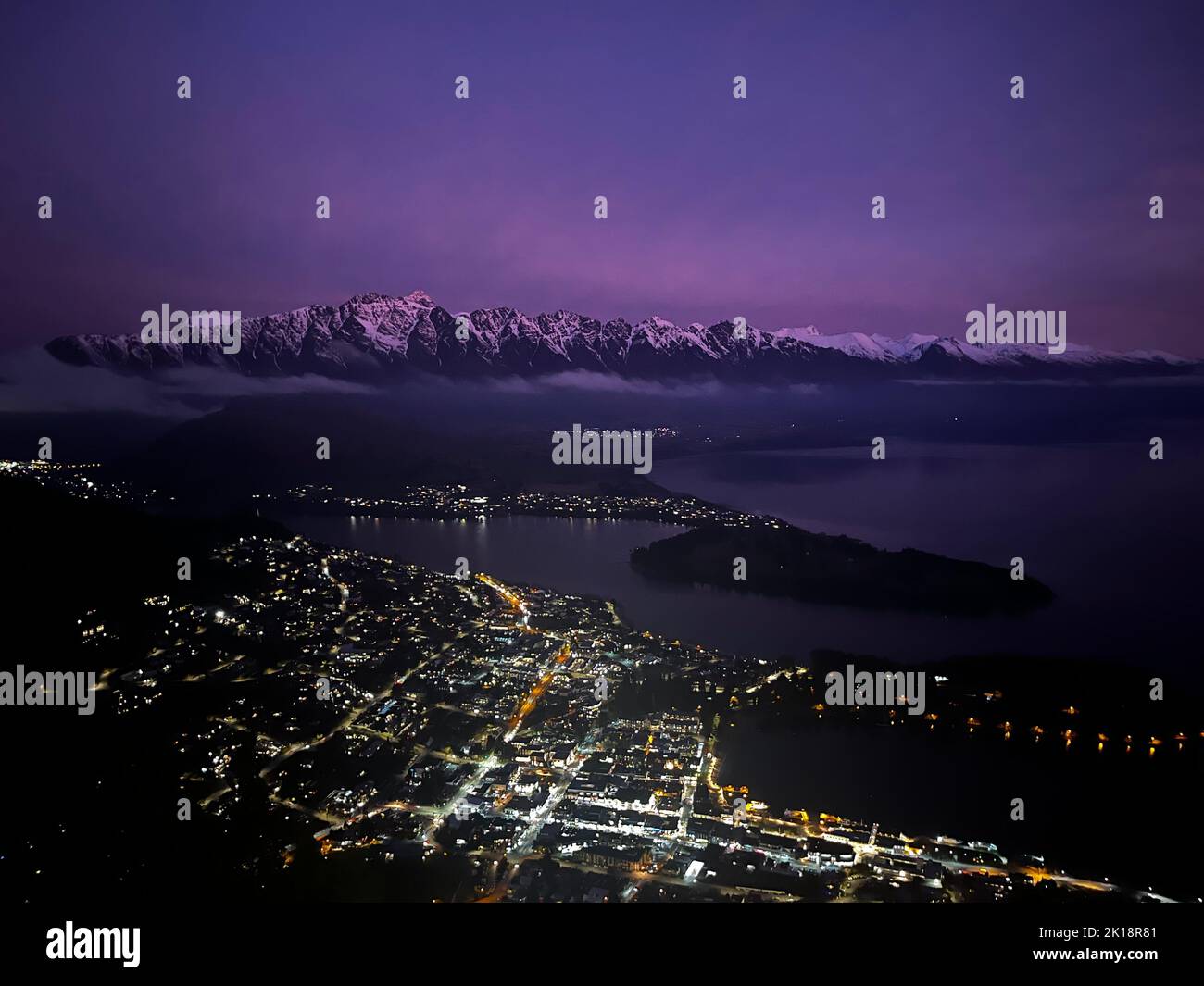 A mesmerizing aerial view of an illuminated city with snowy mountains ...