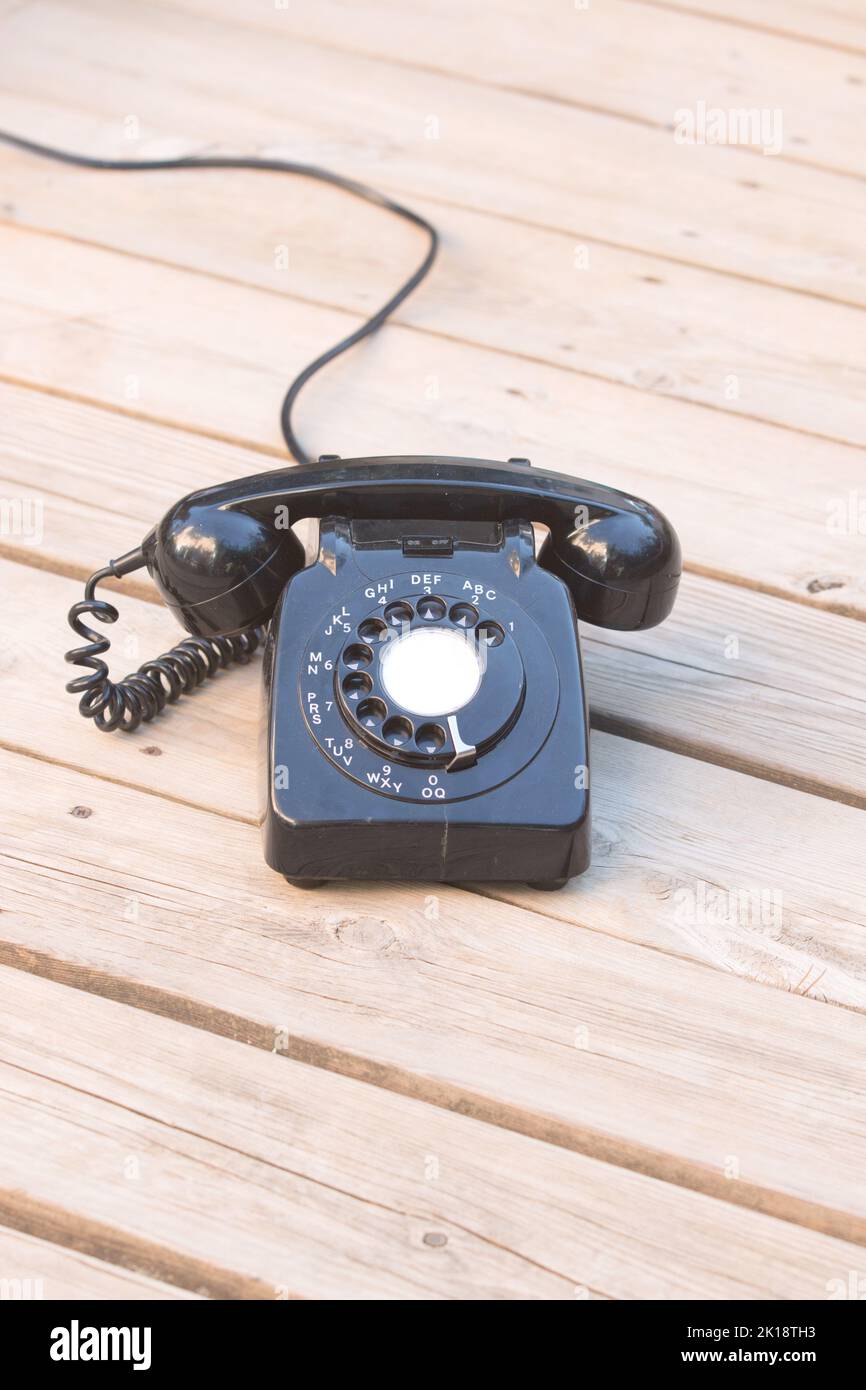 Old fashioned rotary dial analogue telephone on wooden floorboards ...