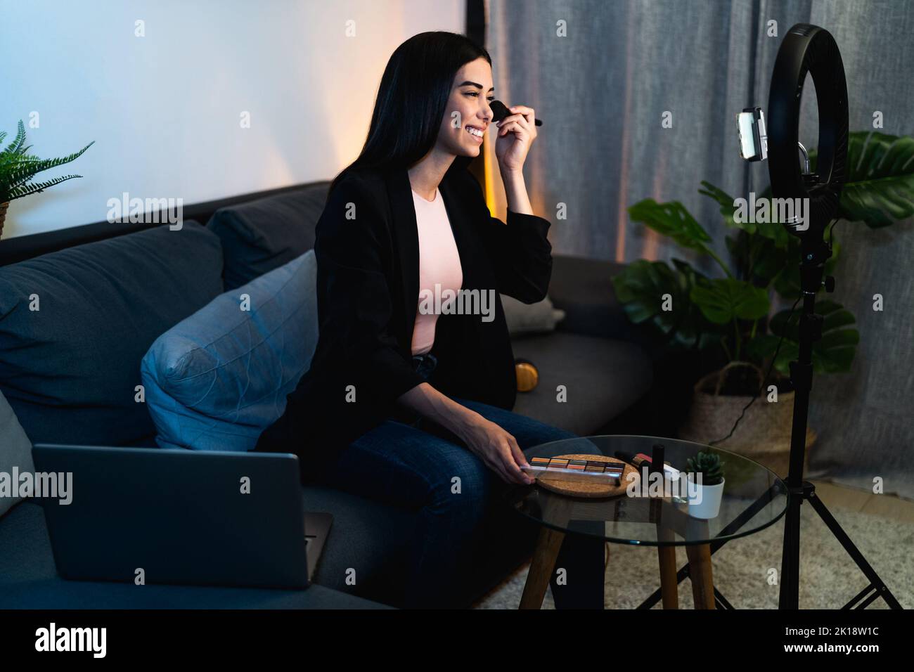 Young woman vlogging online with smartphone cam and ring led from home ...