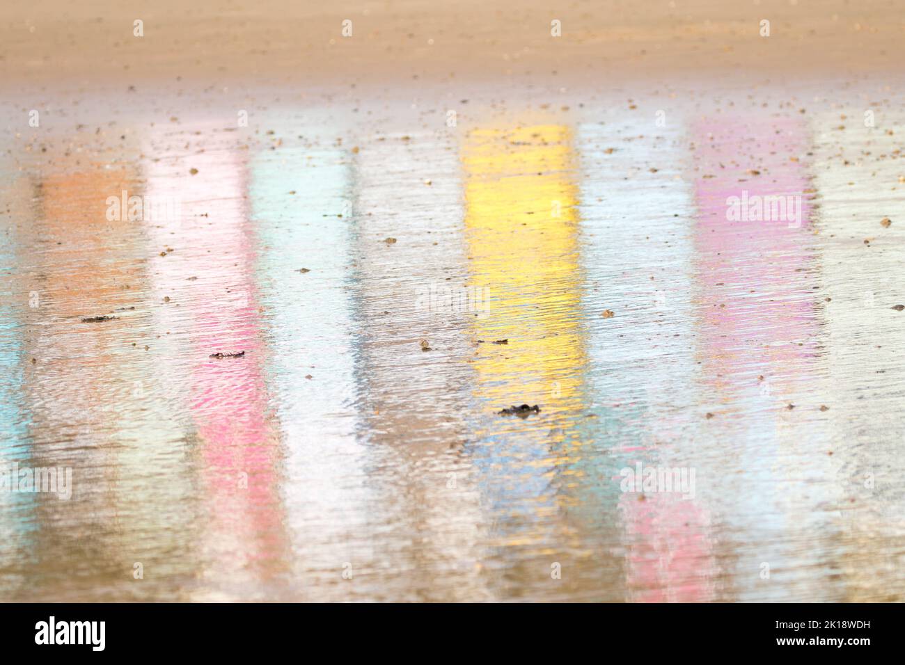 Reflections of multi-coloured beach huts on the wet sand at Walton on ...