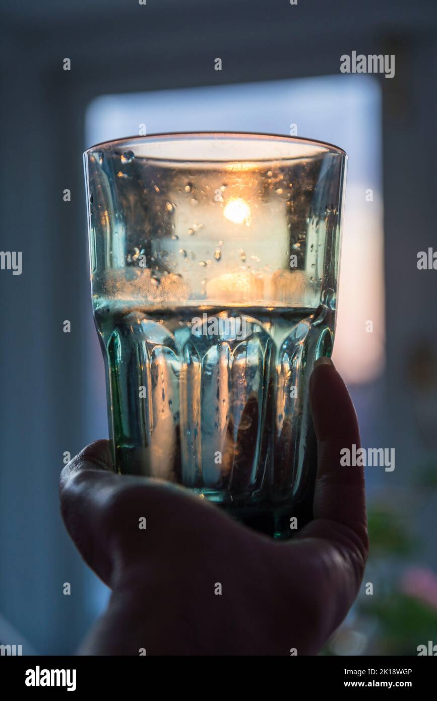 Hand holding empty glass with sunlight reflecting through the glass ...