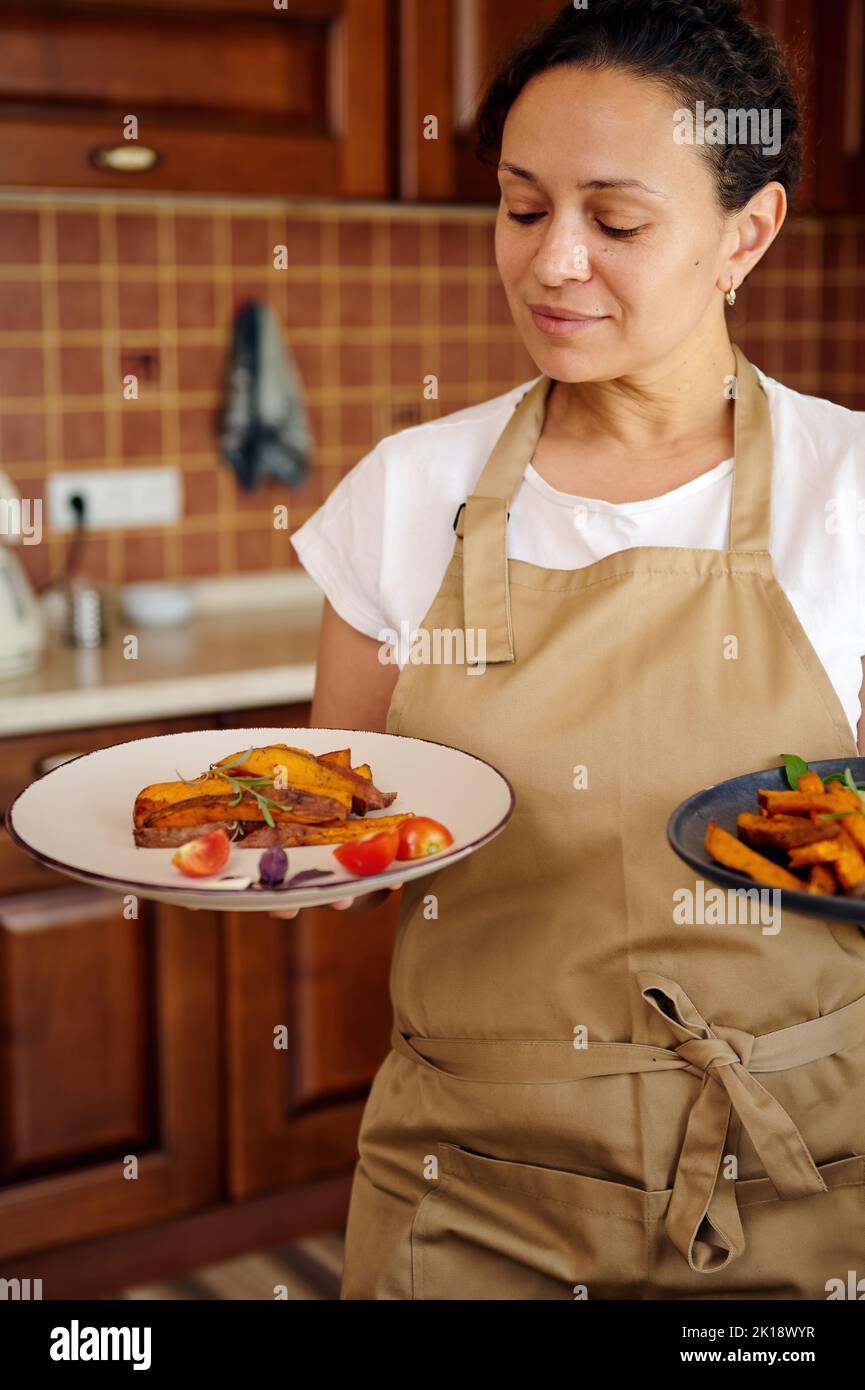 Beautiful woman, a housewife in beige chef's apron carrying served ...