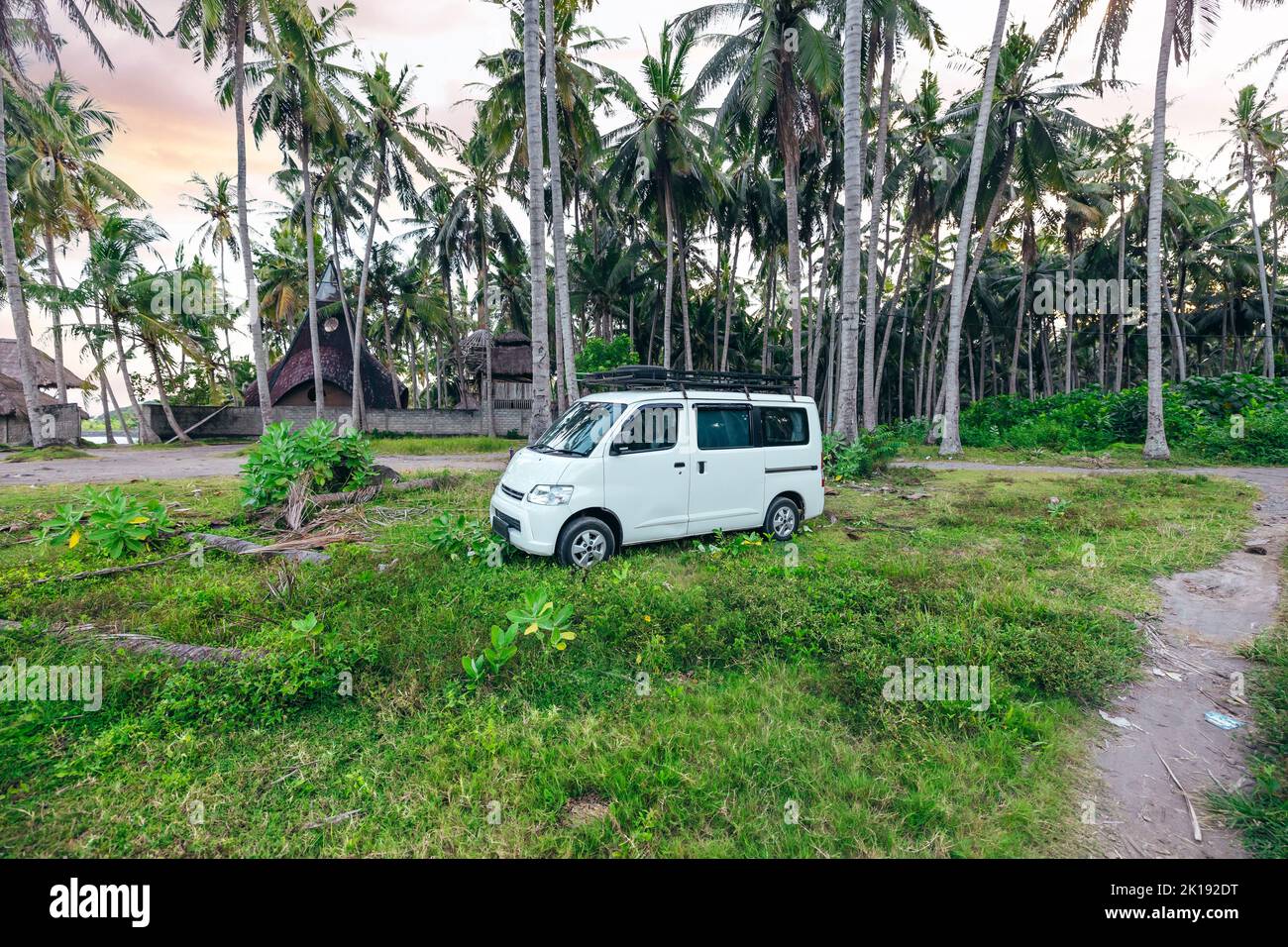wide landscape of a white camper van parked in a tropical green field ...