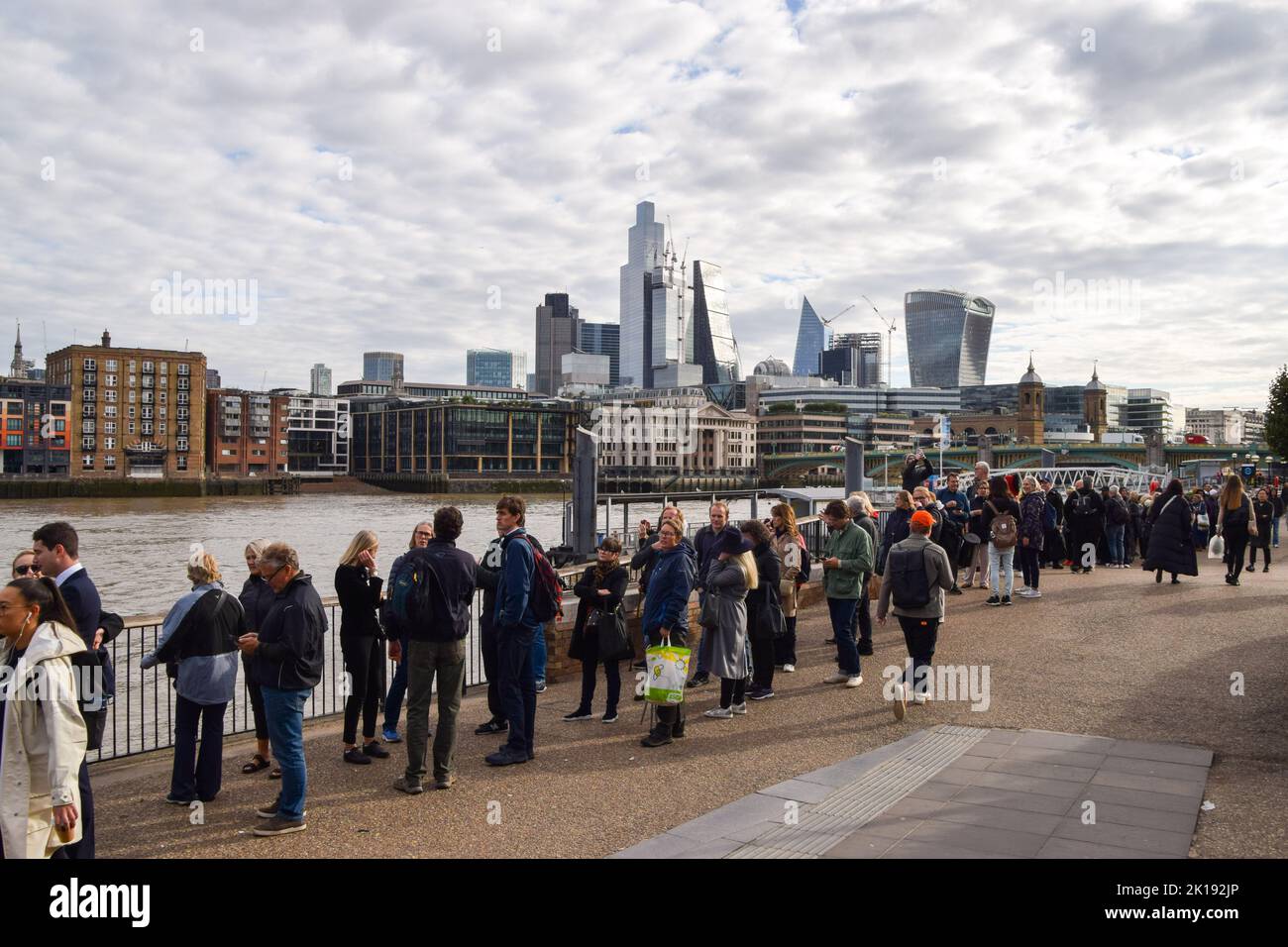 The queue passes by the City of London skyline near Millennium Bridge ...
