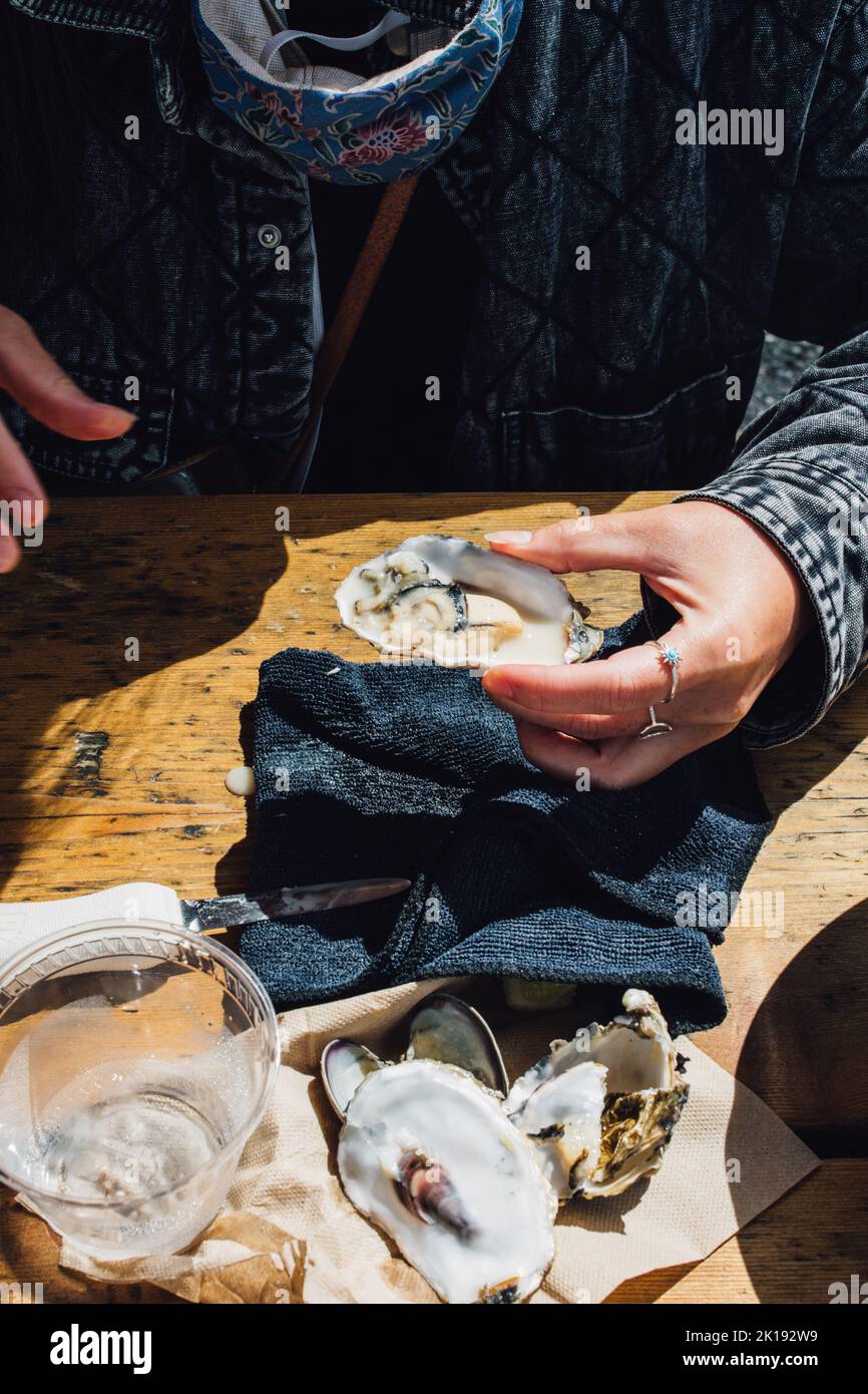 woman shucking and eating oysters at outdoor restaurant Stock Photo - Alamy