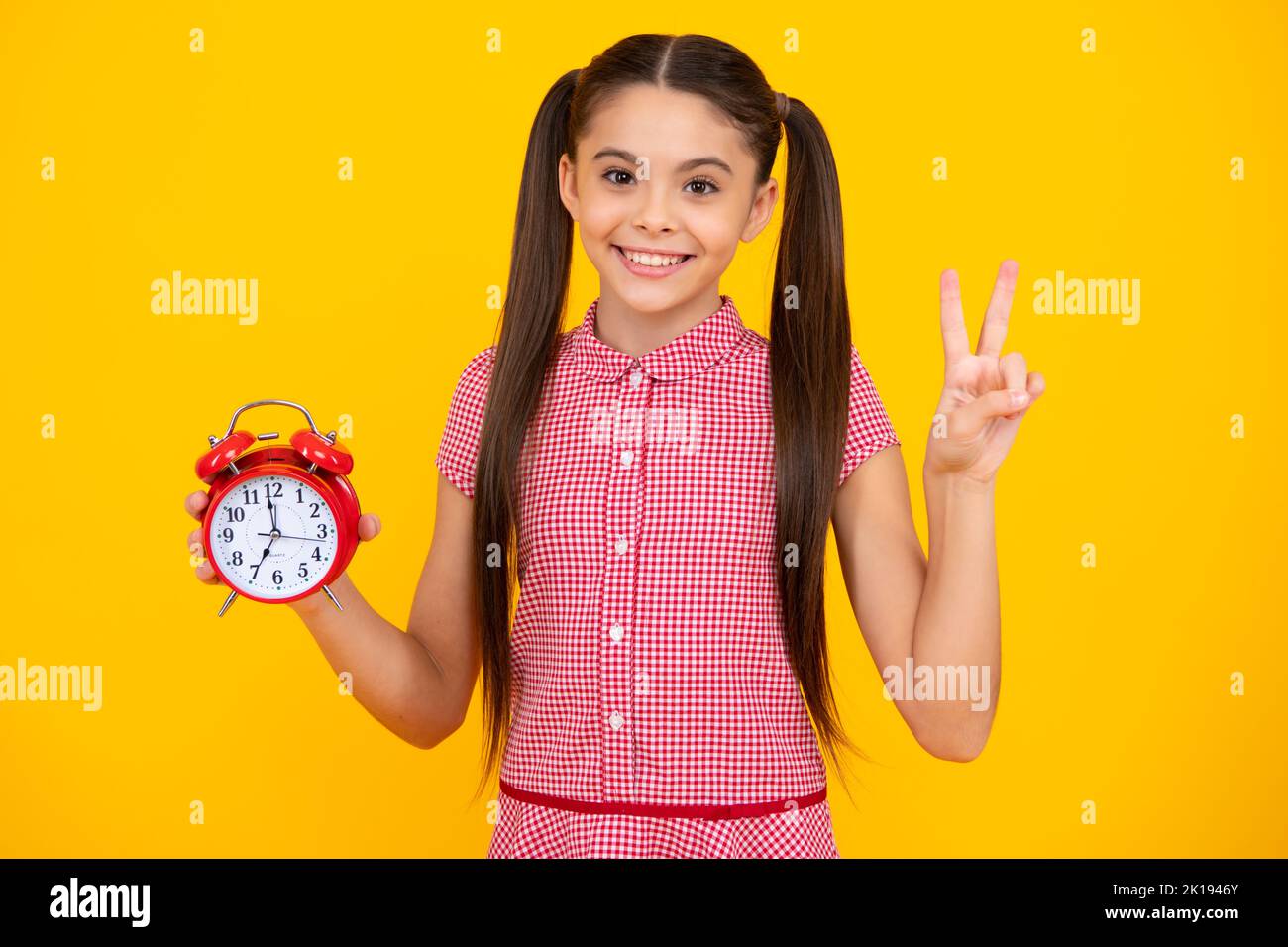 Teen student girl hold clock isolated on yellow background. Time to ...