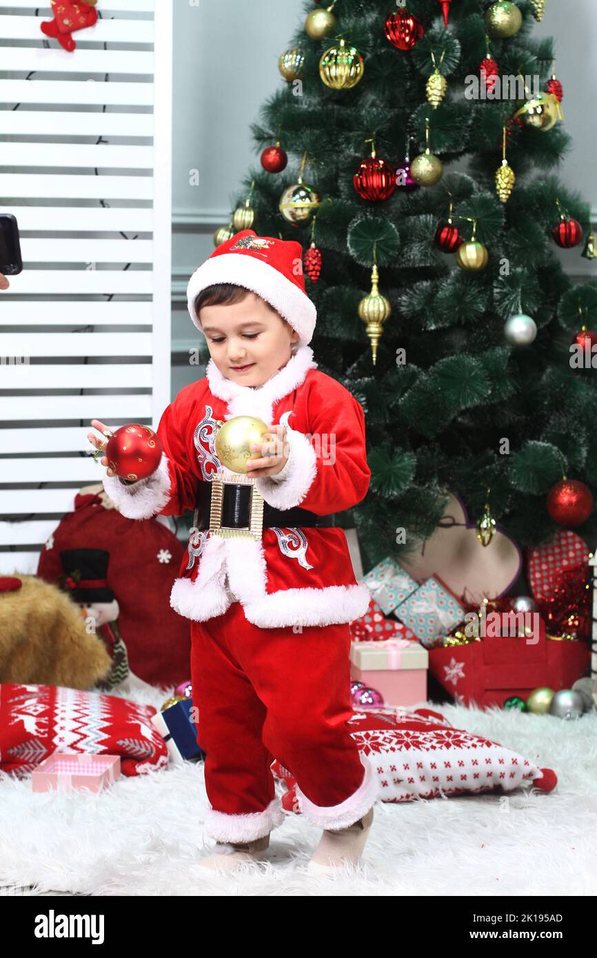 Cute baby wearing a red santa claus costume on a couch at home in ...