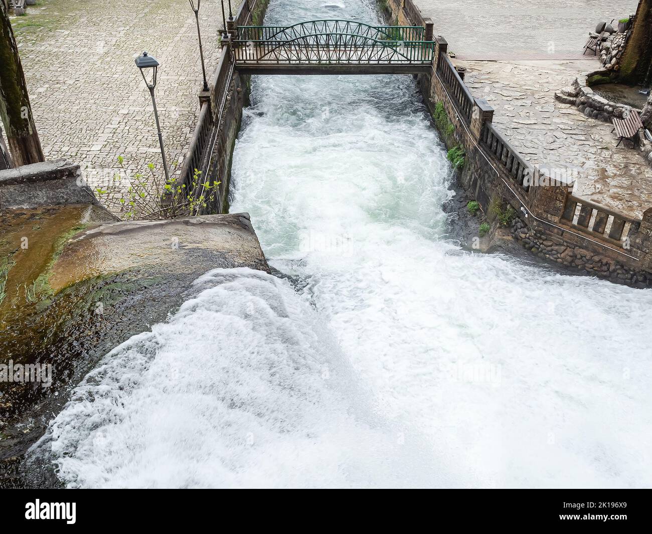 Waterfall flowing into the river under the bridge. Top view of the ...