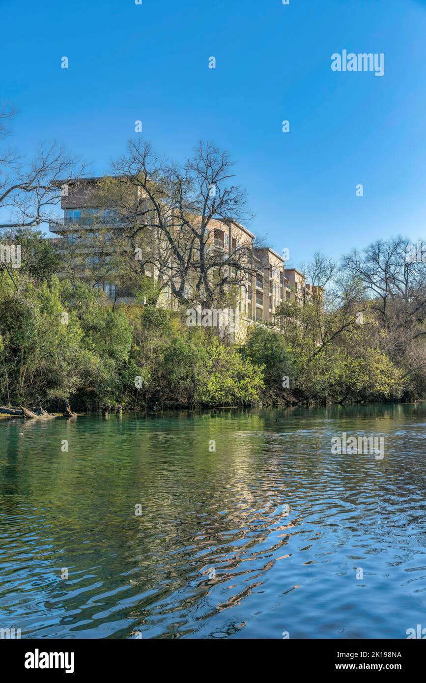 Colorado River with trees and luxury apartments exterior against blue ...