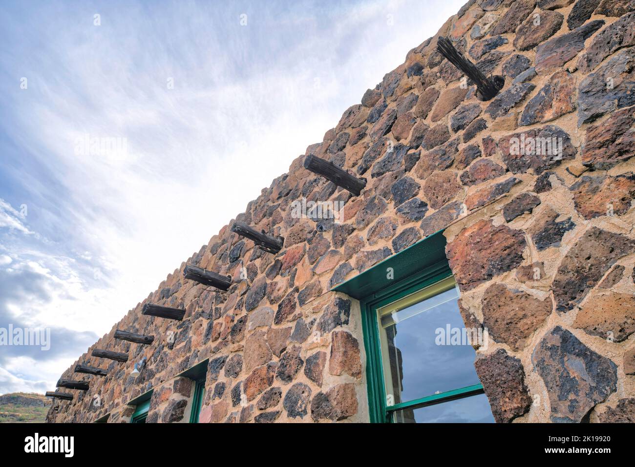 Tucson, Arizona- Stone house with vigas and green window frame. Low ...