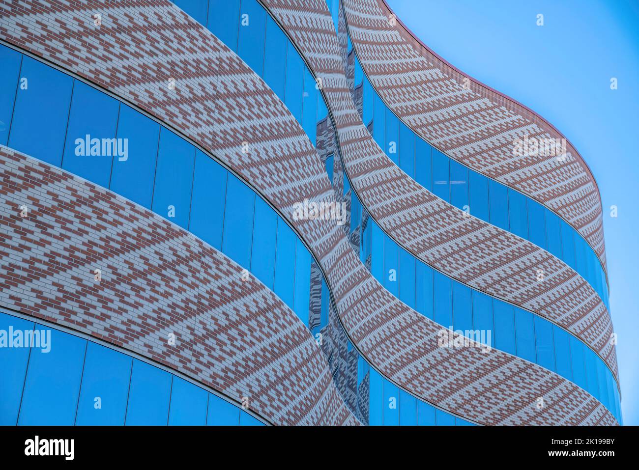 Curved modern building with bricks and reflective glass walls at ...