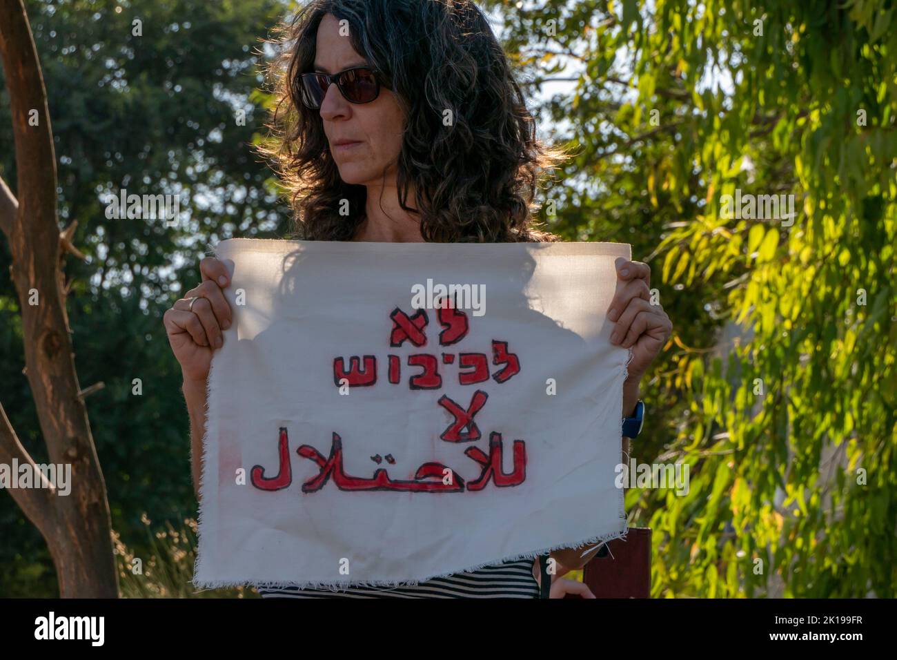 An Israeli left-wing activist holds a sign in Arabic and Hebrew which ...
