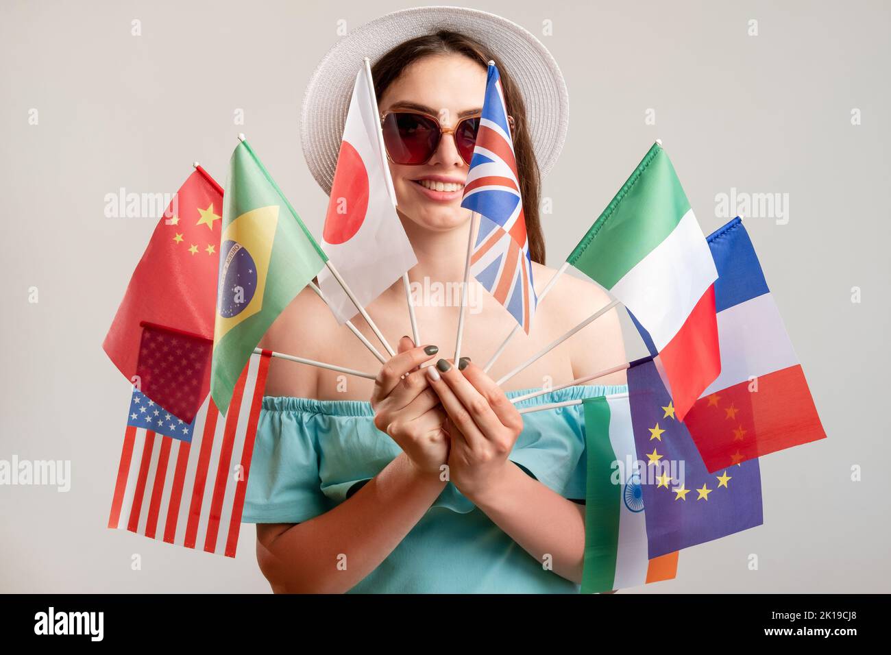 World travel. Visa office. Happy woman in summer outfit holding many international hand flags ...