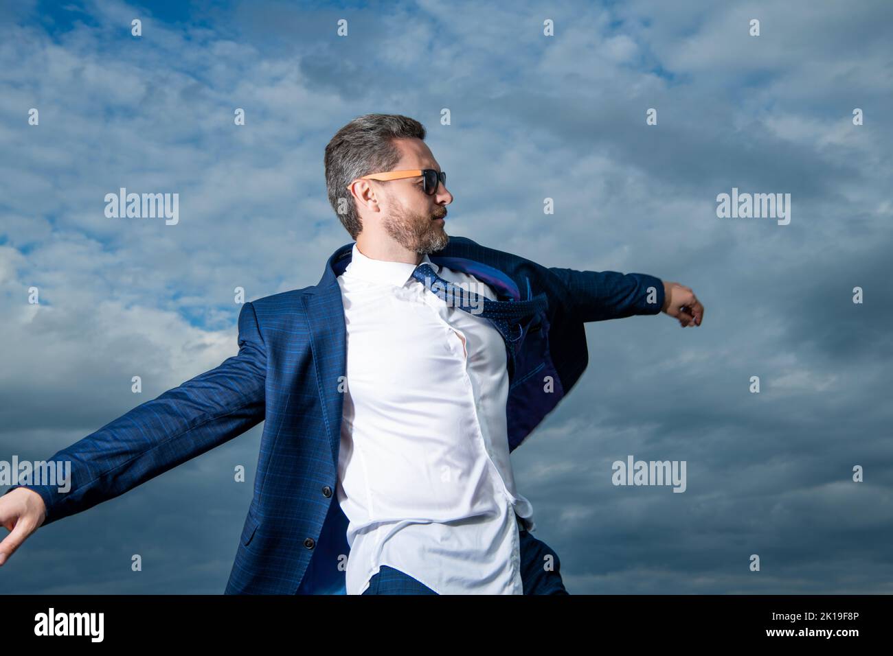 Businessman walking in open suit jacket fluttering in carefree wind ...