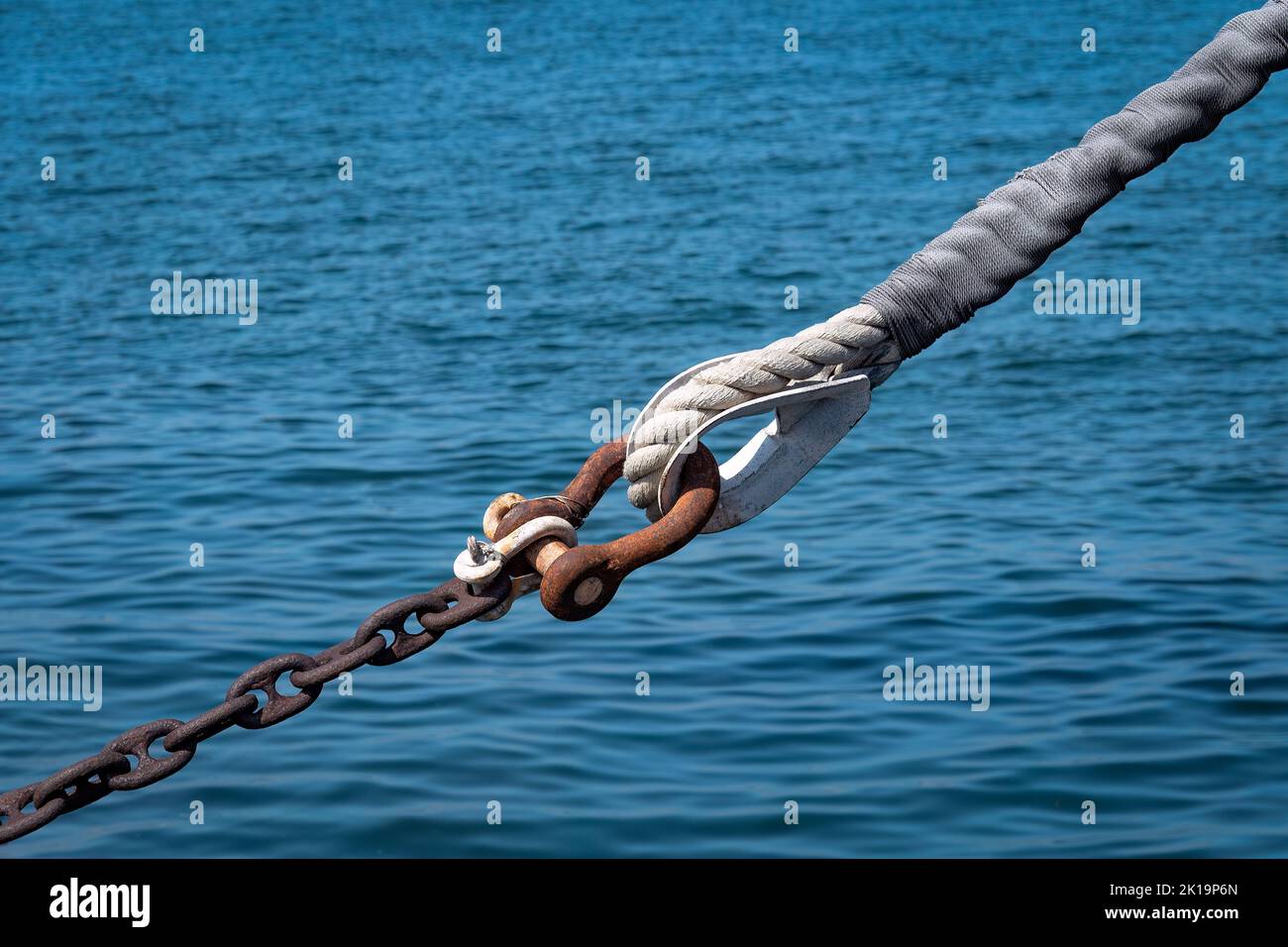 Old stud link docking chain connected to twisted fiber line by rusted ...