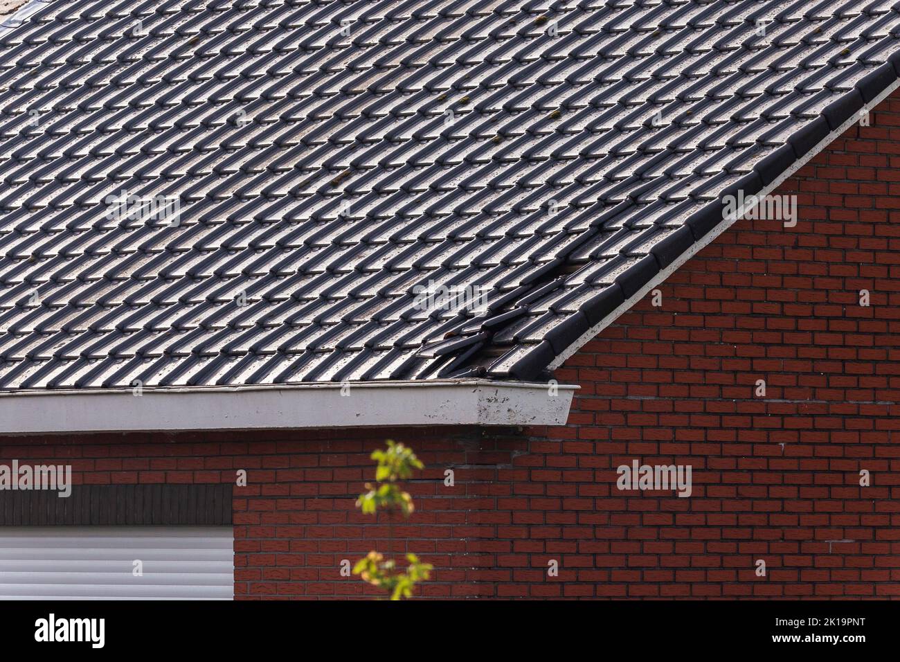 A close up portrait of a destroyed black tile roof of a house. The ...