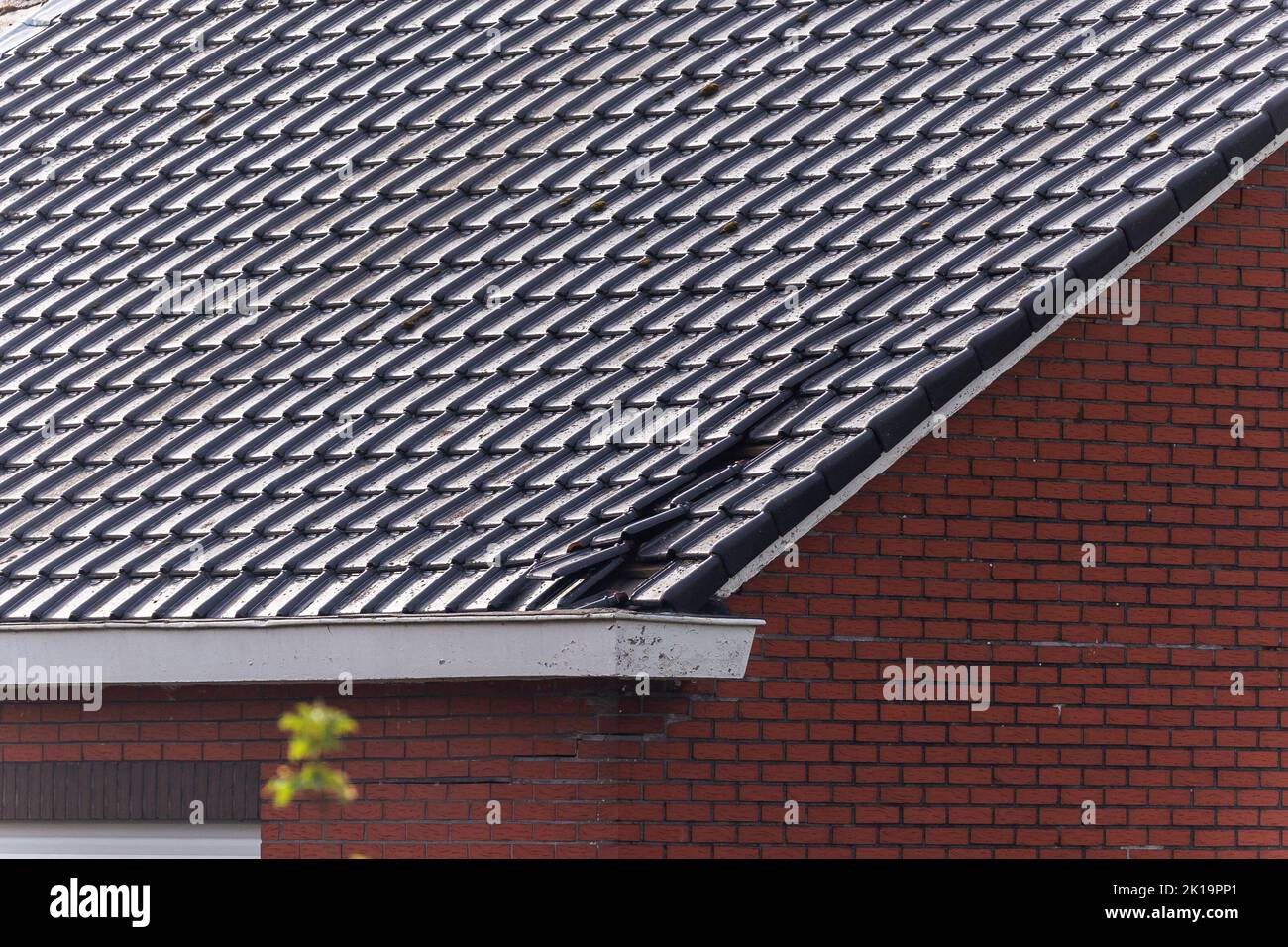 A portrait of a damaged black tile roof of a house. The building got ...