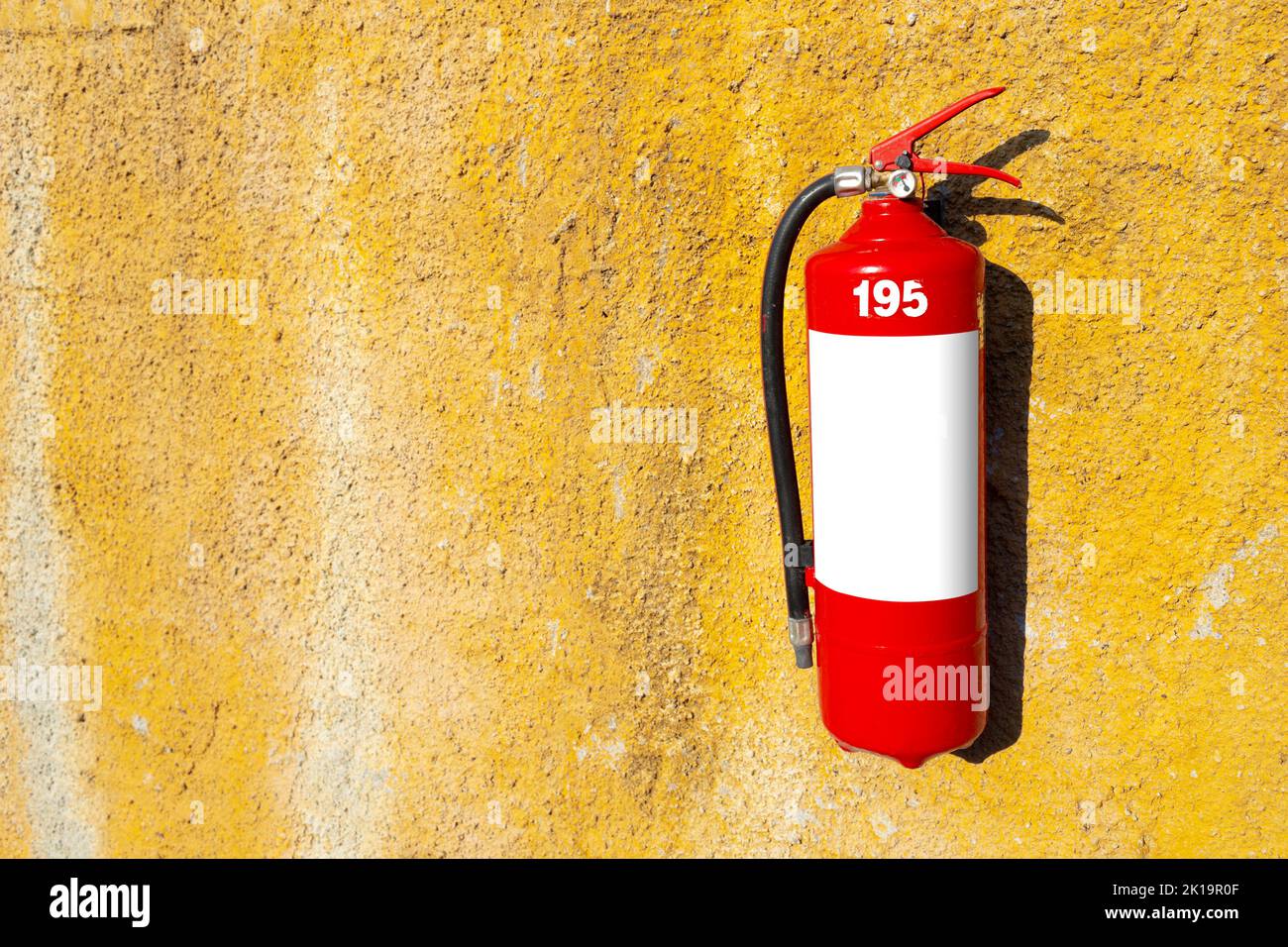 Fire extinguisher on the yellow old wall Stock Photo - Alamy