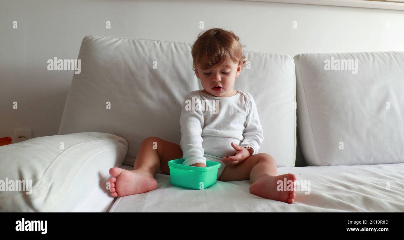 Calm cute baby sitting on couch eating snack Stock Photo - Alamy