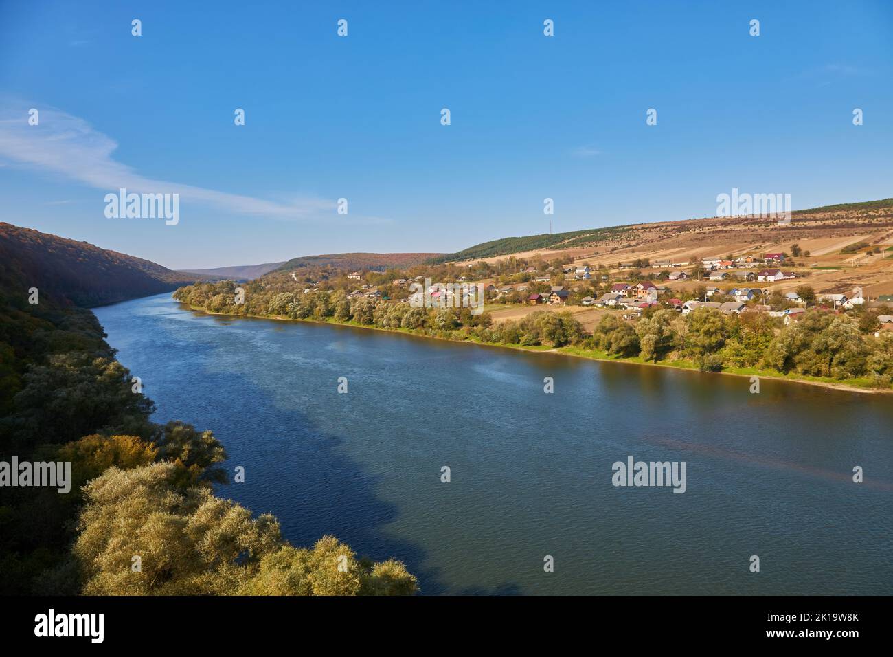 a wide river in the autumn season, forest trees with yellowed foliage ...