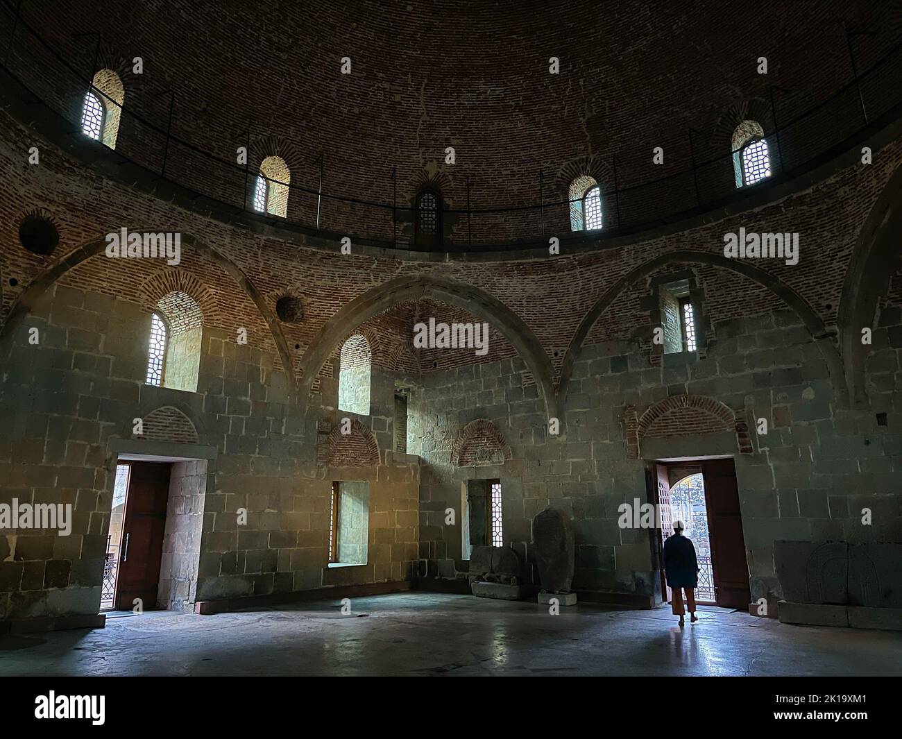 Woman walking inside medieval castle with arched windows and stone dome ...