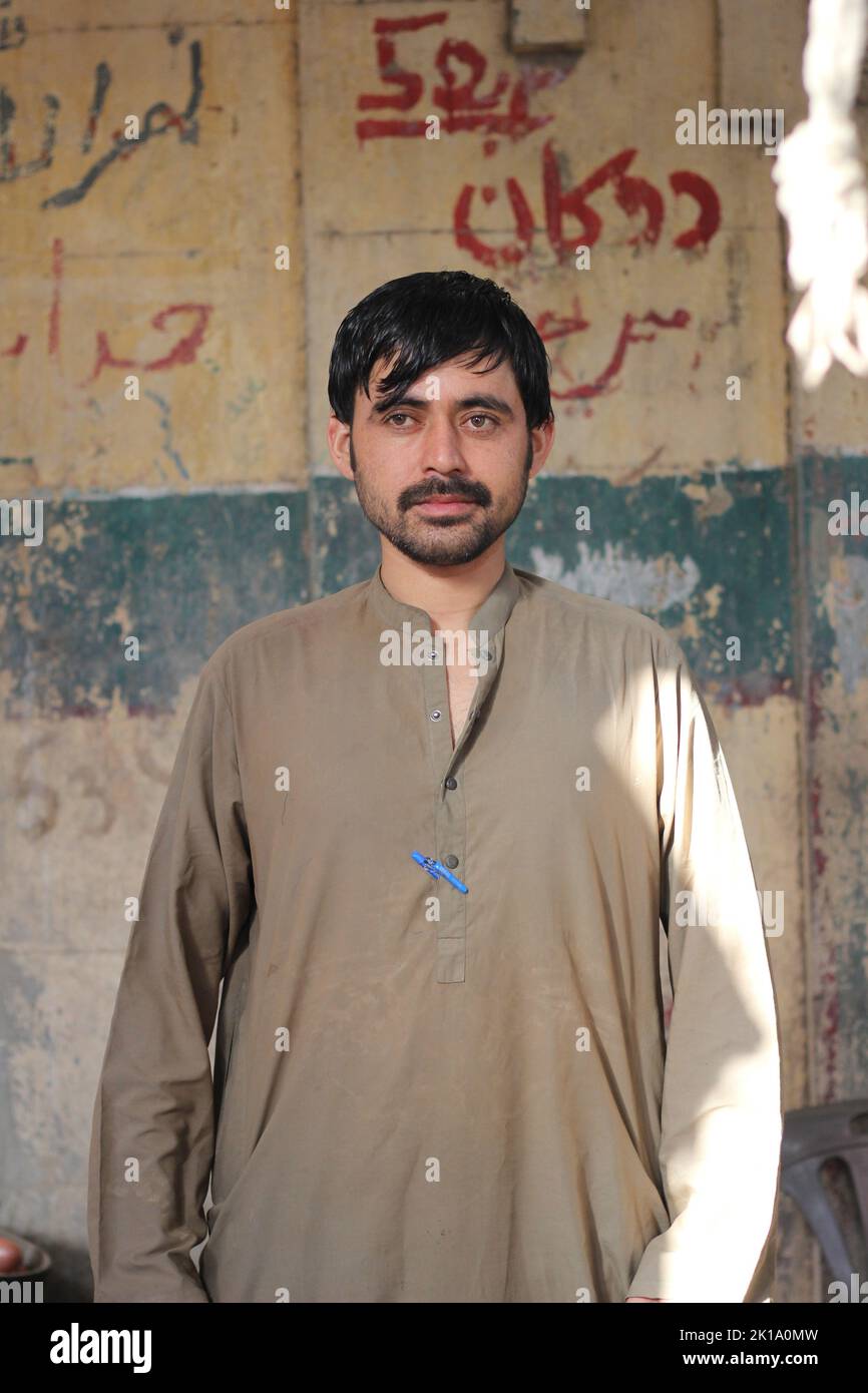 A vertical shallow focus of a Pakistani male with a mustache standing ...