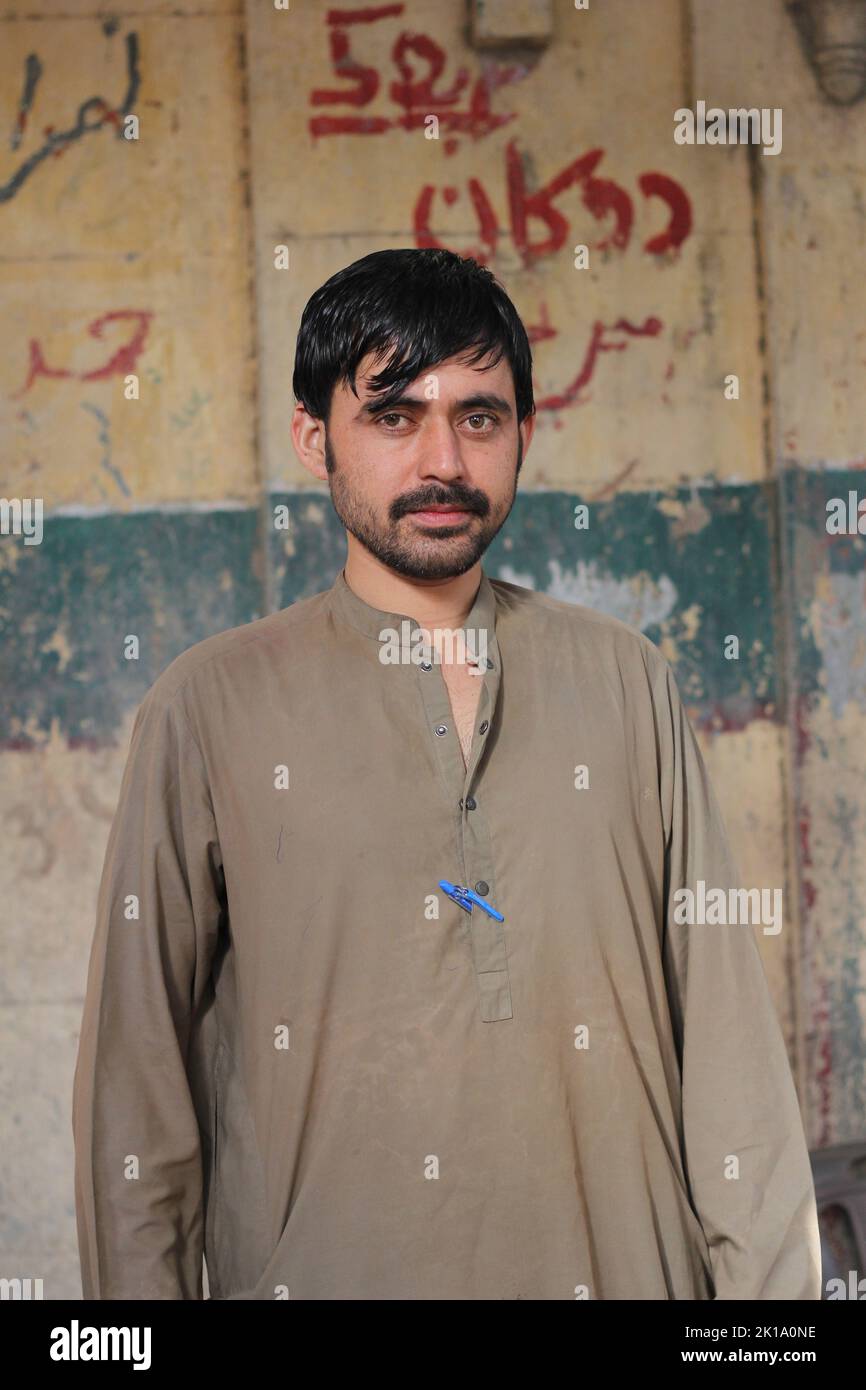 A vertical shallow focus of a Pakistani male with a mustache standing ...