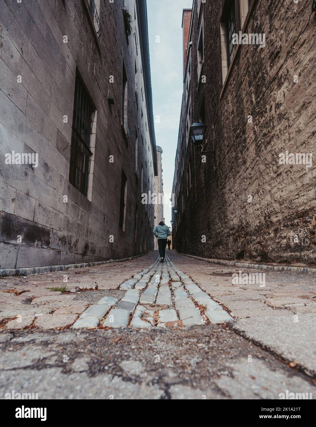 A vertical shot of a person walking on a narrow alley Stock Photo - Alamy