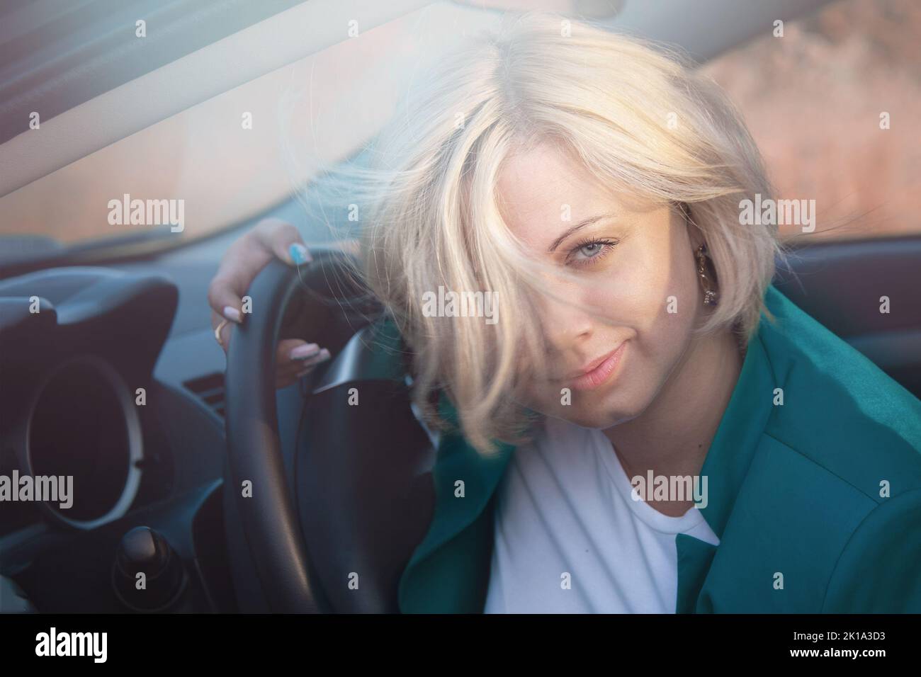 Beautiful blonde driving a car. Body positive girl smiling at the wheel ...