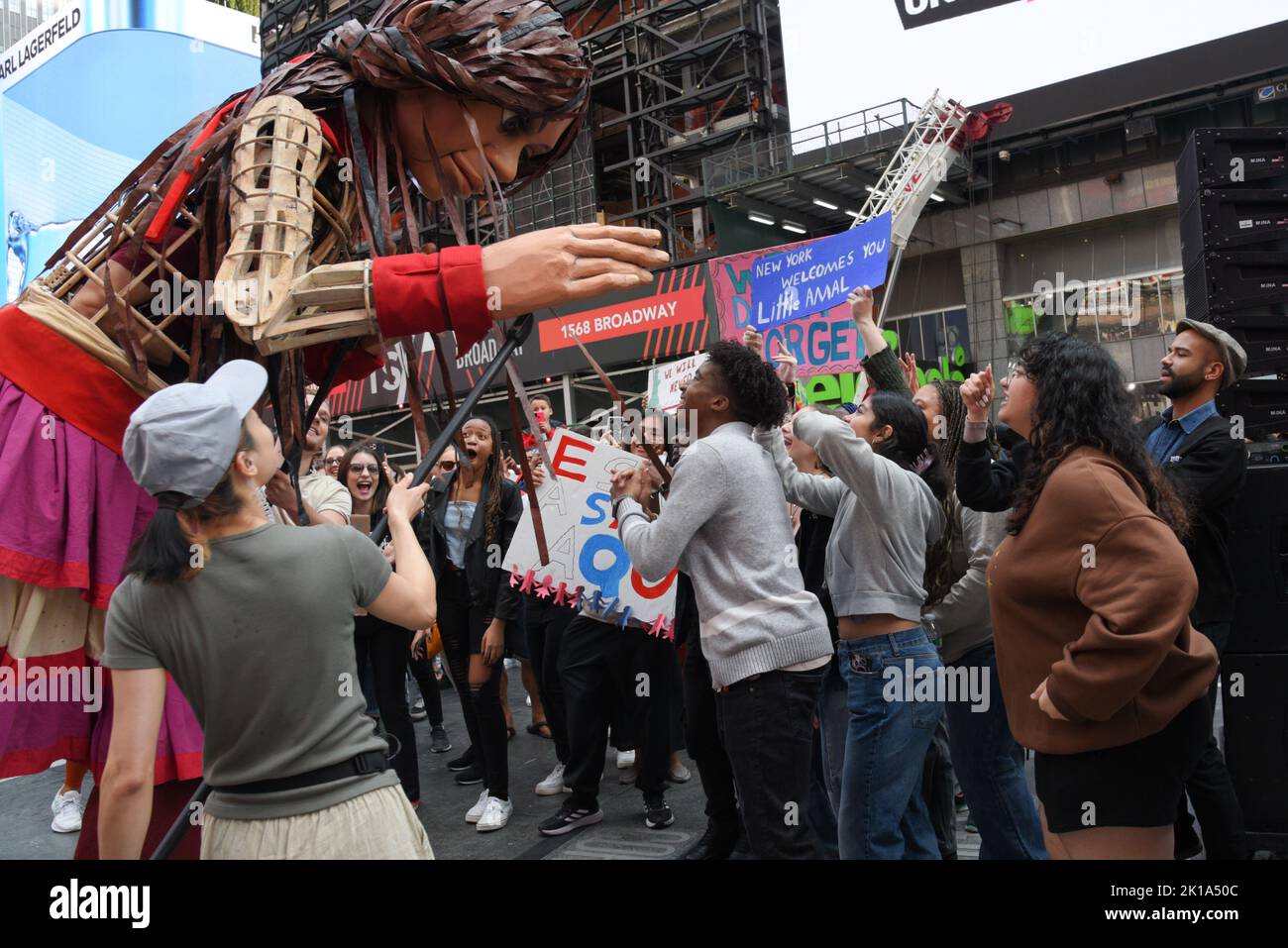 Students interact with Little Amal, while holding placards in Times ...