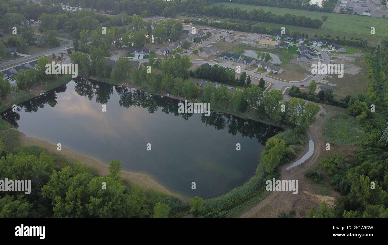 An aerial view of a pond surrounded by green nature in a residential ...