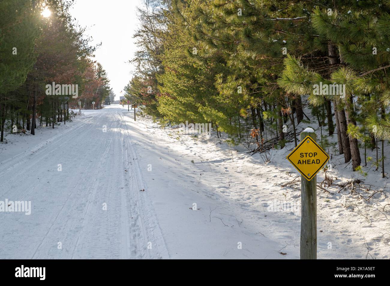 Stop ahead sign on a snow covered snowmobile and hiking trail through a ...