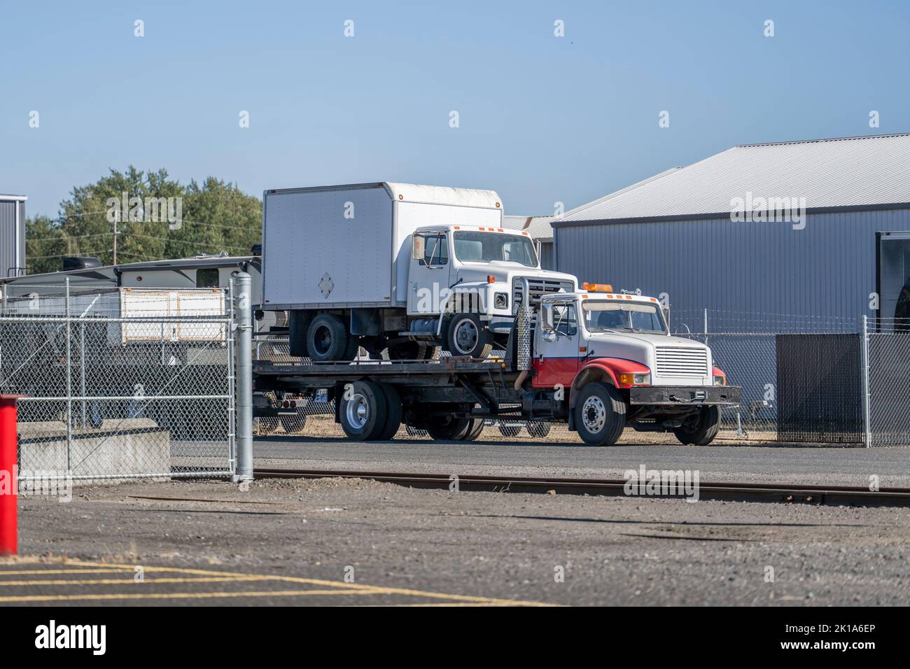 Day cab big rig semi towing truck carry another truck with box trailer ...
