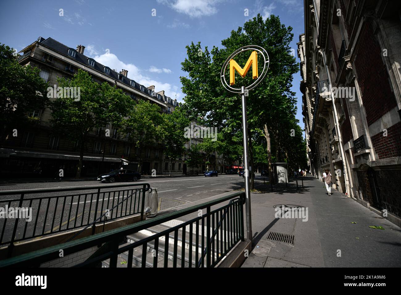 Sign with the subway logo (yellow symbol) in front of a parisian metro ...