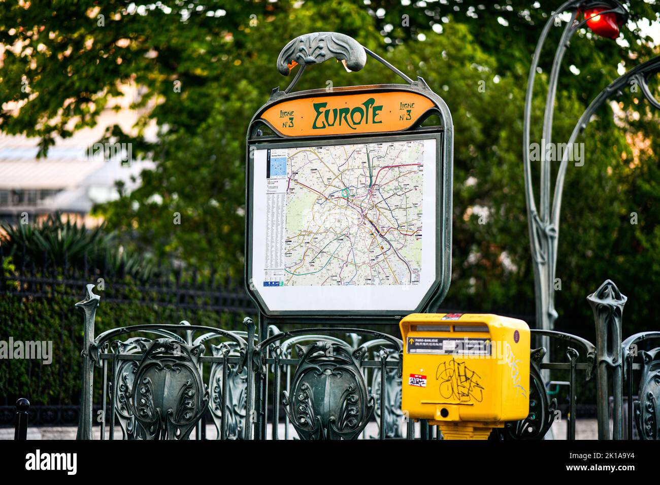 Sign with the subway logo (yellow symbol) in front of a parisian metro ...