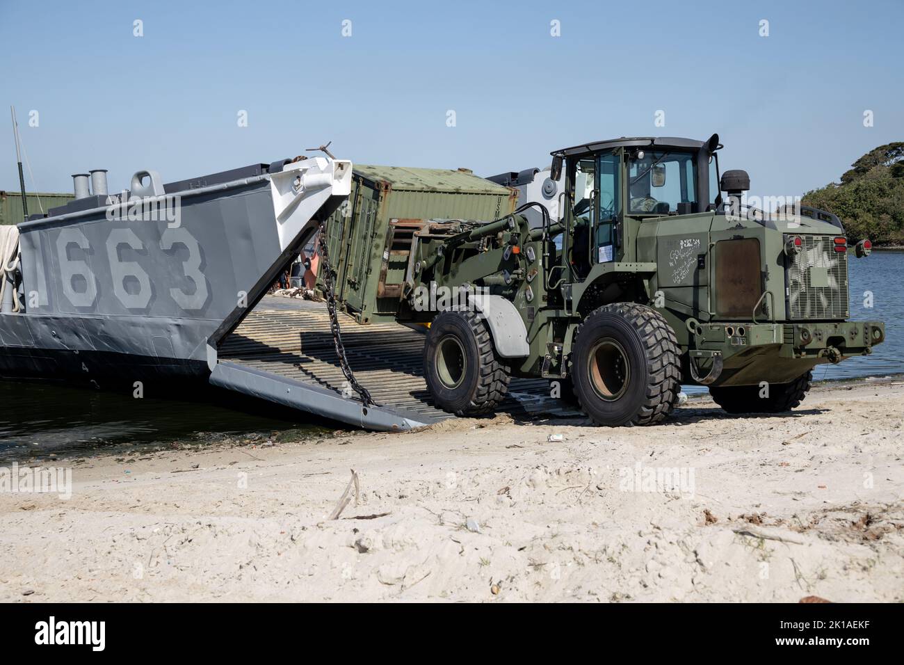 A U.S. Marine Corps forklift moves storage containers ashore from ...