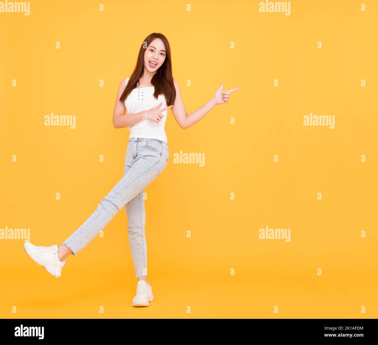 Full length of Happy young woman standing and pointing Stock Photo - Alamy
