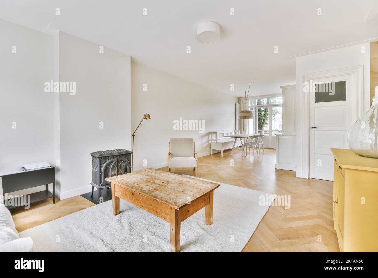 Shabby wooden table with chairs and vase located near comfortable couch ...