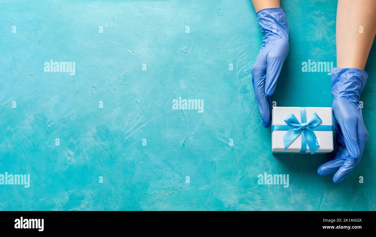 Gift box. COVID-19 prevention. Hands in protective gloves present with ...