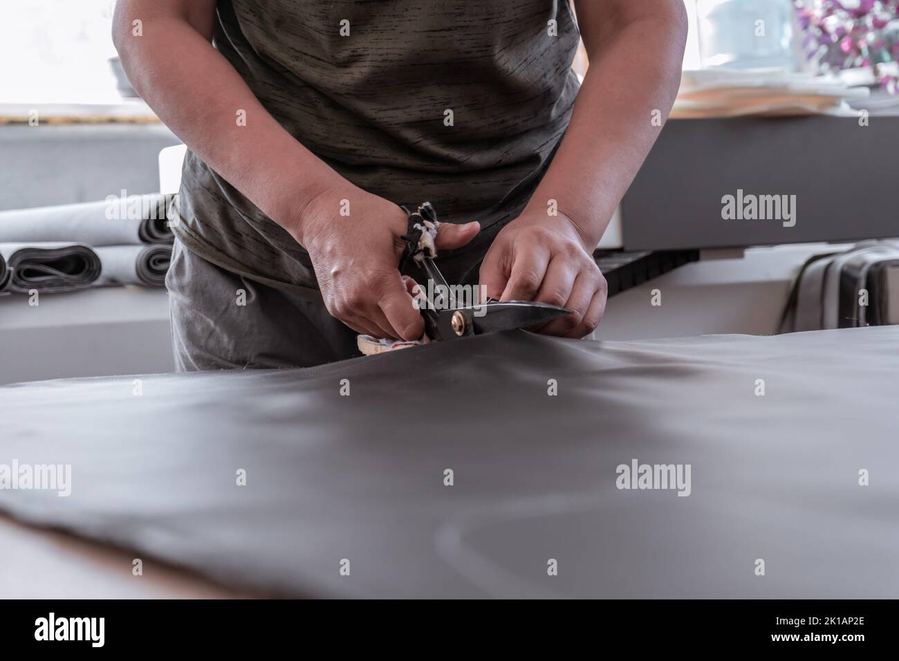 A cutter cuts fabric with scissors in a sewing workshop Stock Photo - Alamy