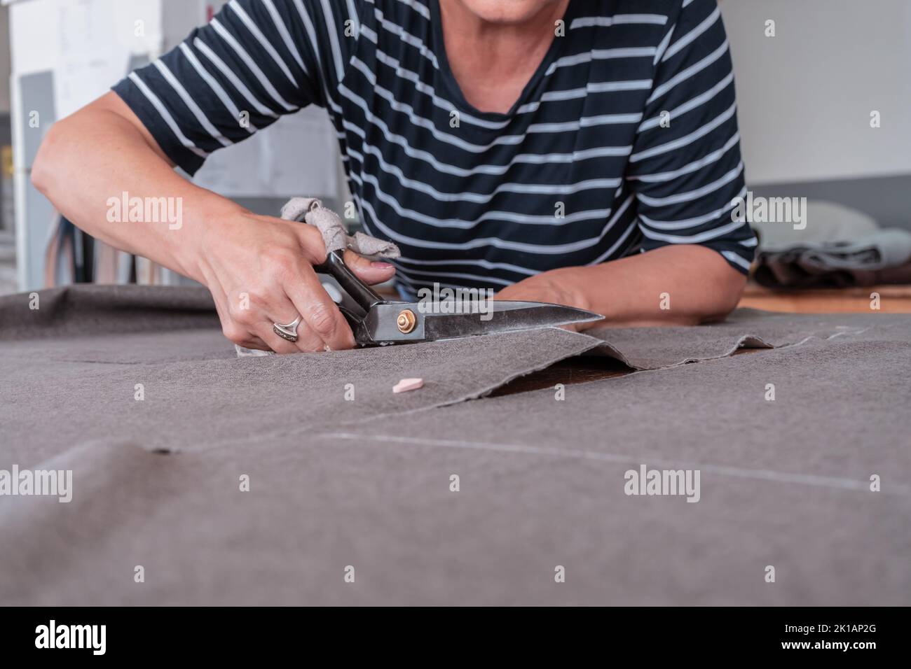 A cutter cuts fabric with scissors in a sewing workshop Stock Photo - Alamy