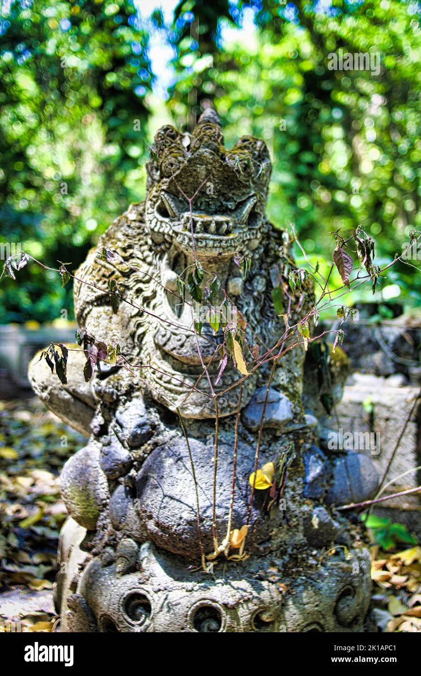 A closeup shot of a traditional stone statue in the garden with blur ...
