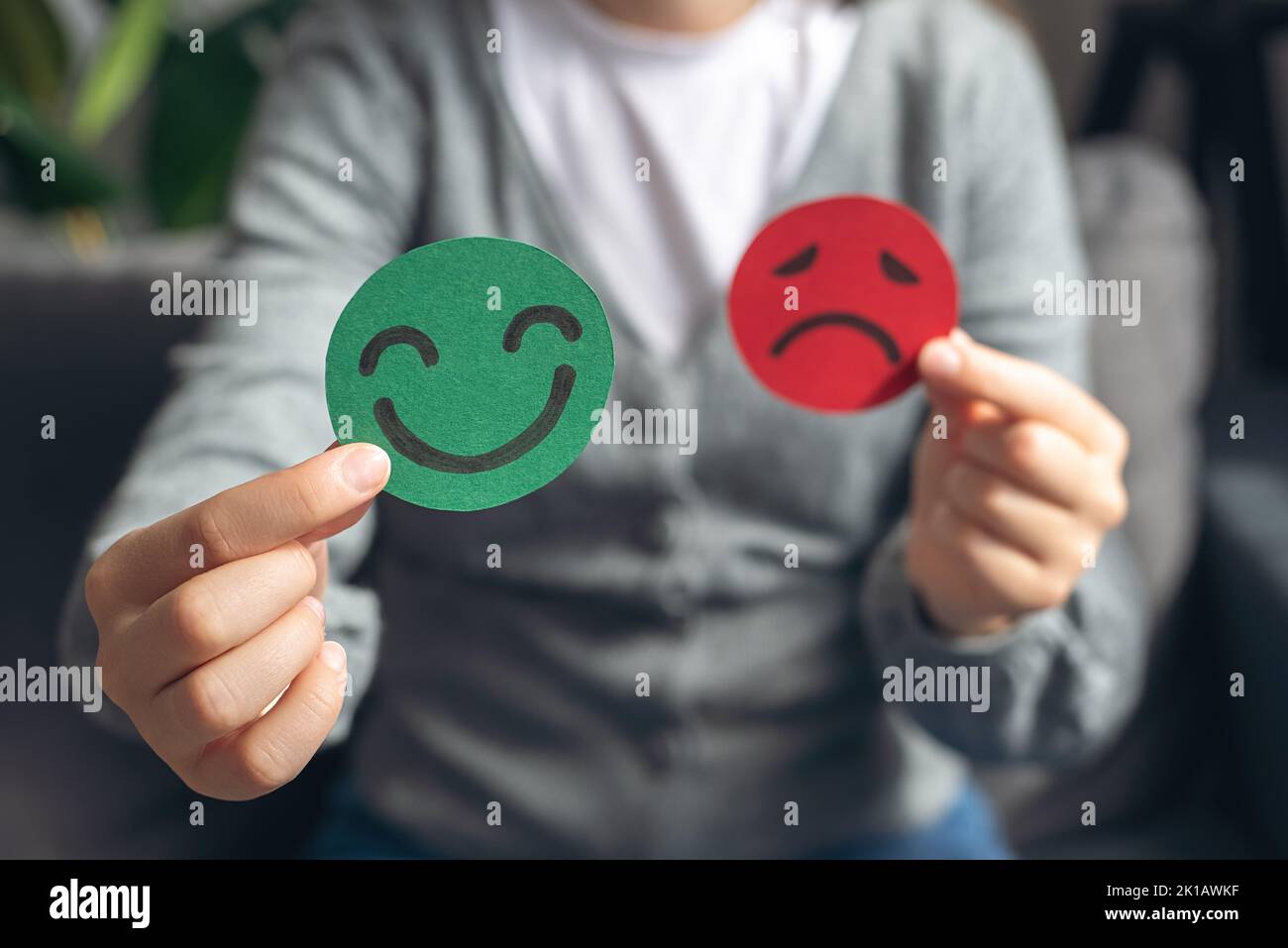 Selective focus of female hands holding happy and angry face paper sit ...