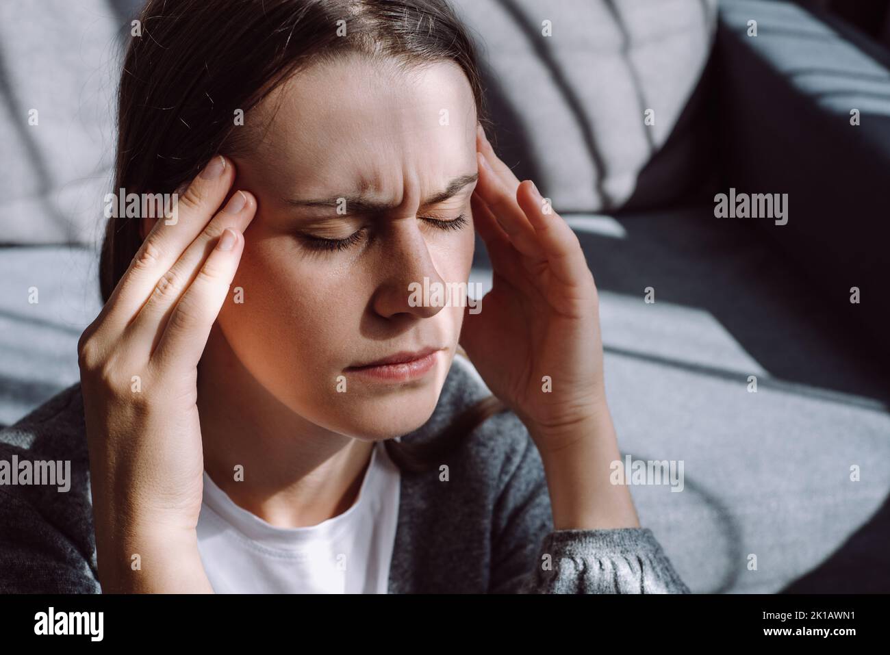 Close up of stressed young caucasian woman touching head and feels ...