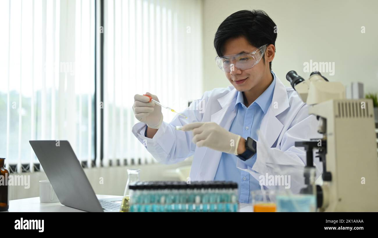 Young man researcher conducting experiment with test tubes and ...