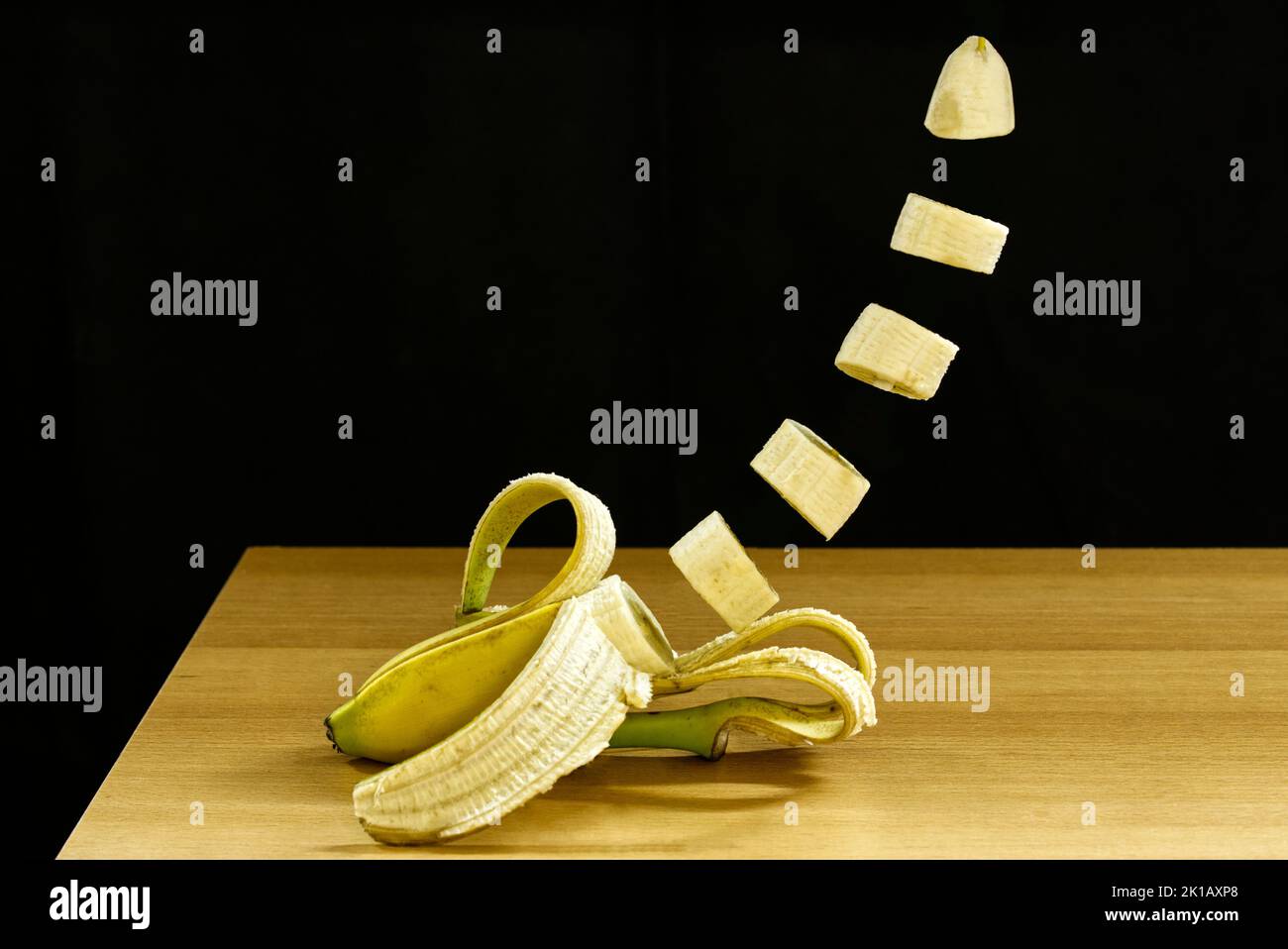 A peeled cut banana with pieces in the air Stock Photo - Alamy